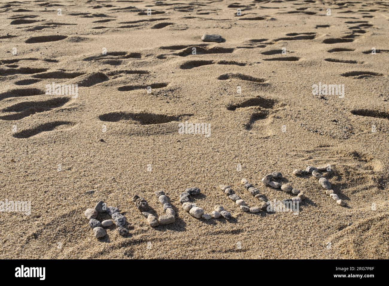 august and summer concept with lettering made on a beach with stones ...