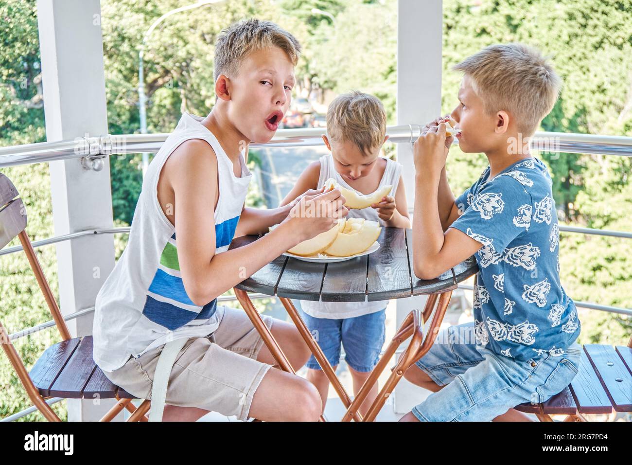 Junior school children and preschooler boy eating fresh melon on hotel ...