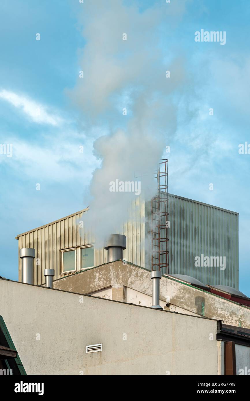 Industrial chimney fume and steam exhaustion on old factory building ...