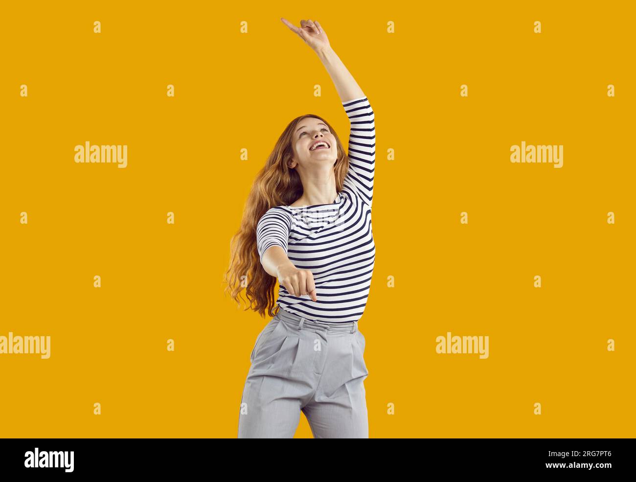 Young woman having fun pretending to be rider and pointing up at copy ...