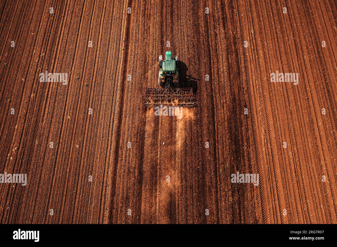 Agricultural tractor with tiller attached performing field tillage ...