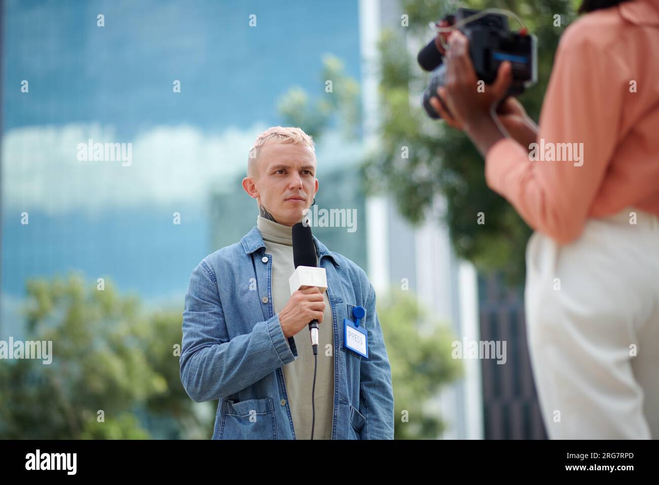 Serious journalist speaking in microphone when filming news report for ...