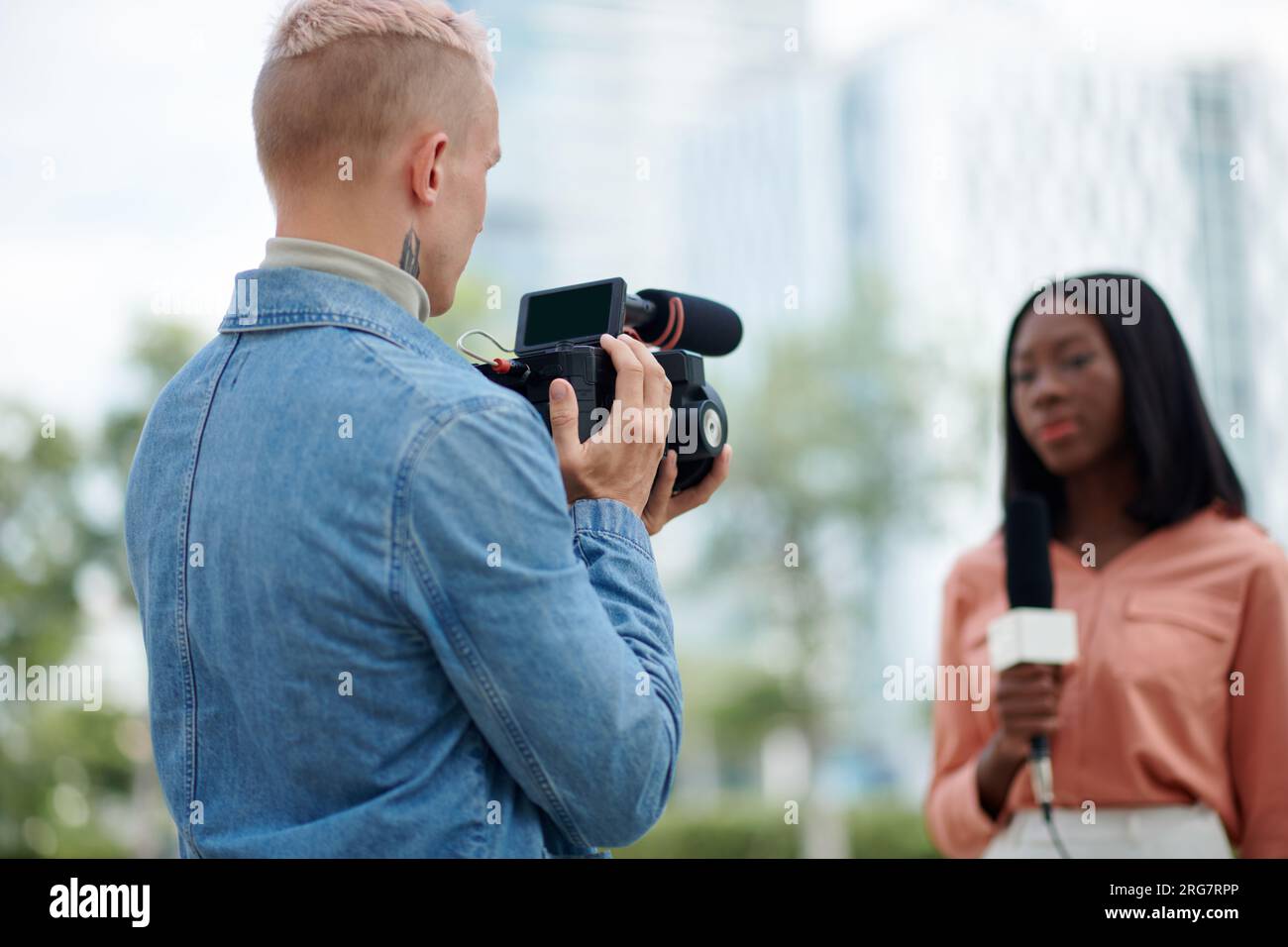 Cameraman filming journalist speaking in microphone Stock Photo - Alamy