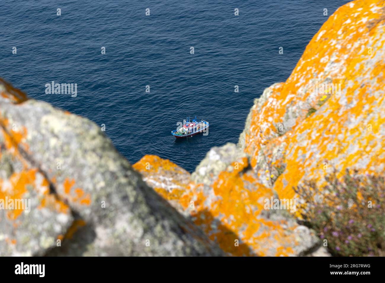 Fishing trawler boat far below steep cliffs Isla del Faro, Cies Islands ...