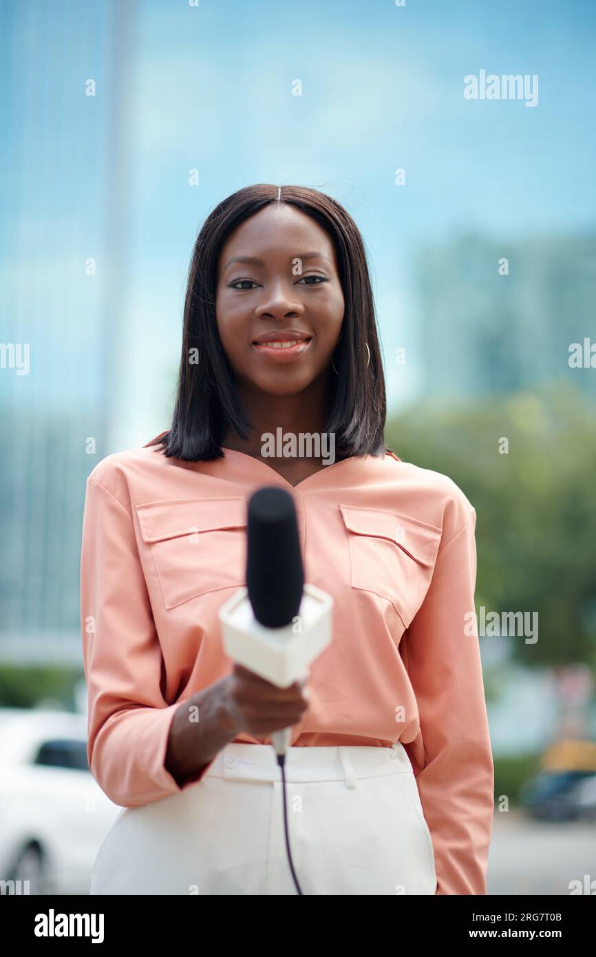 Portrait of smiling journalist with microphone standing outdoors Stock ...