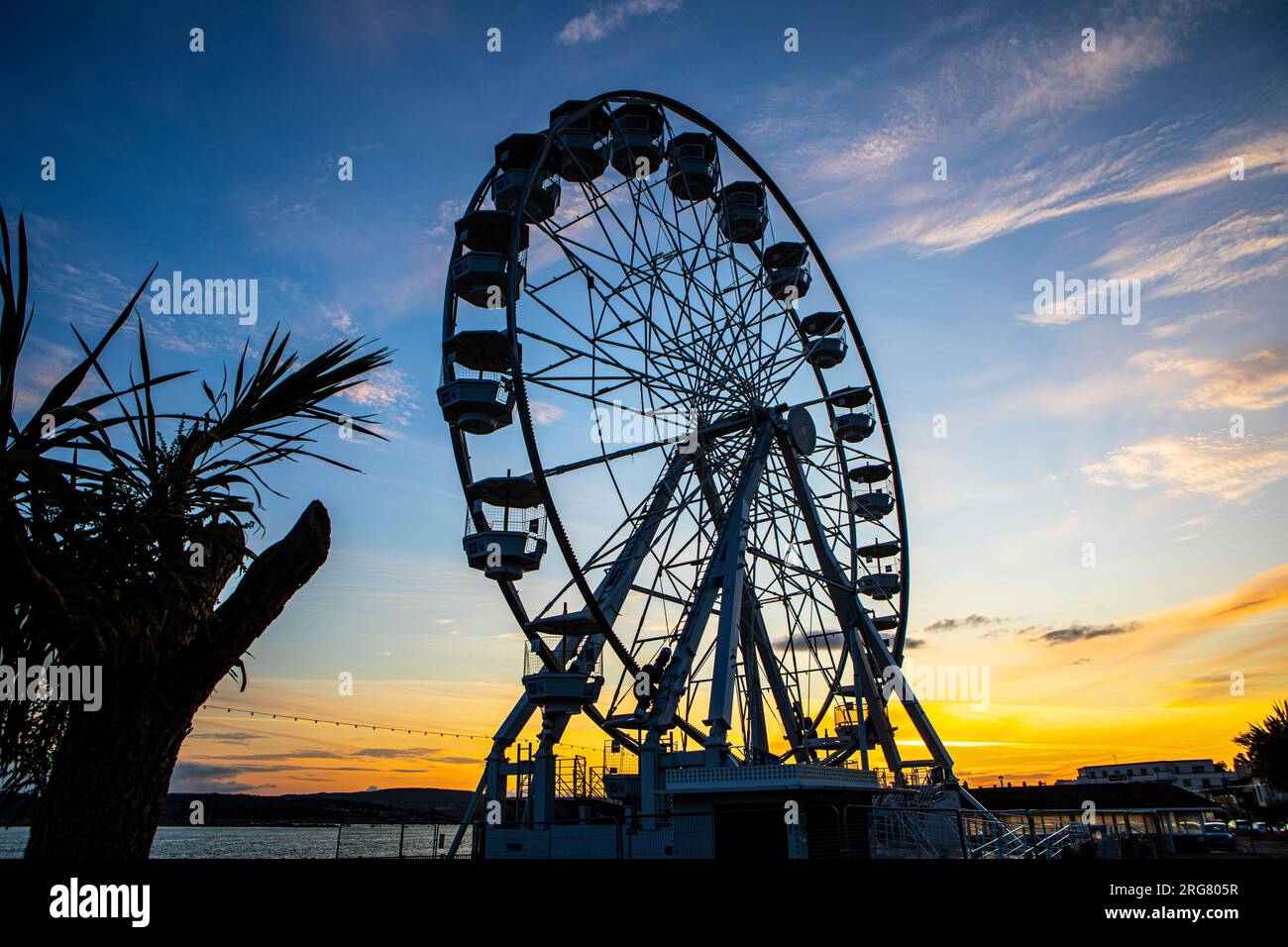 A ferris wheel on Exmouth seafront silhouetted against a vivid sunset ...