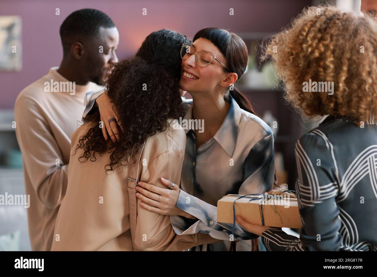 Happy young brunette woman giving hug to African American girl at home ...