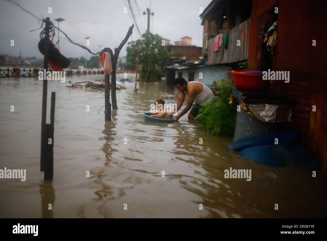 Kathmandu, Nepal. 08th Aug, 2023. A man takes his child outside their flooded home after heavy ...