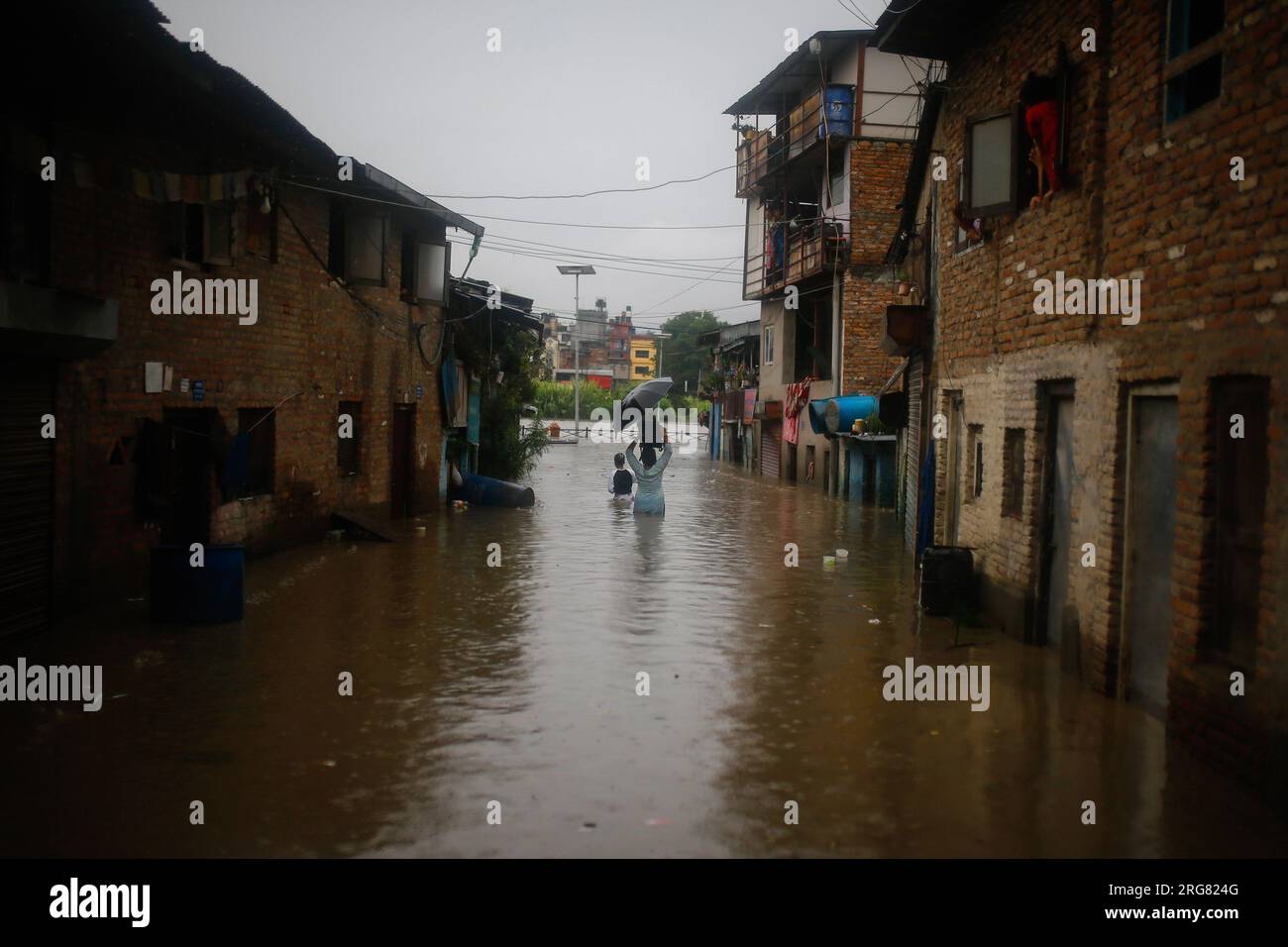 Kathmandu, Nepal. 08th Aug, 2023. A woman carries her belongings while wading through flooded ...