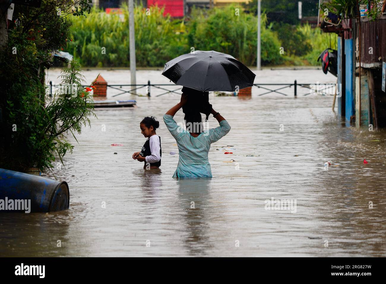 Kathmandu, Nepal. 08th Aug, 2023. A woman carries her belongings while wading through flooded ...
