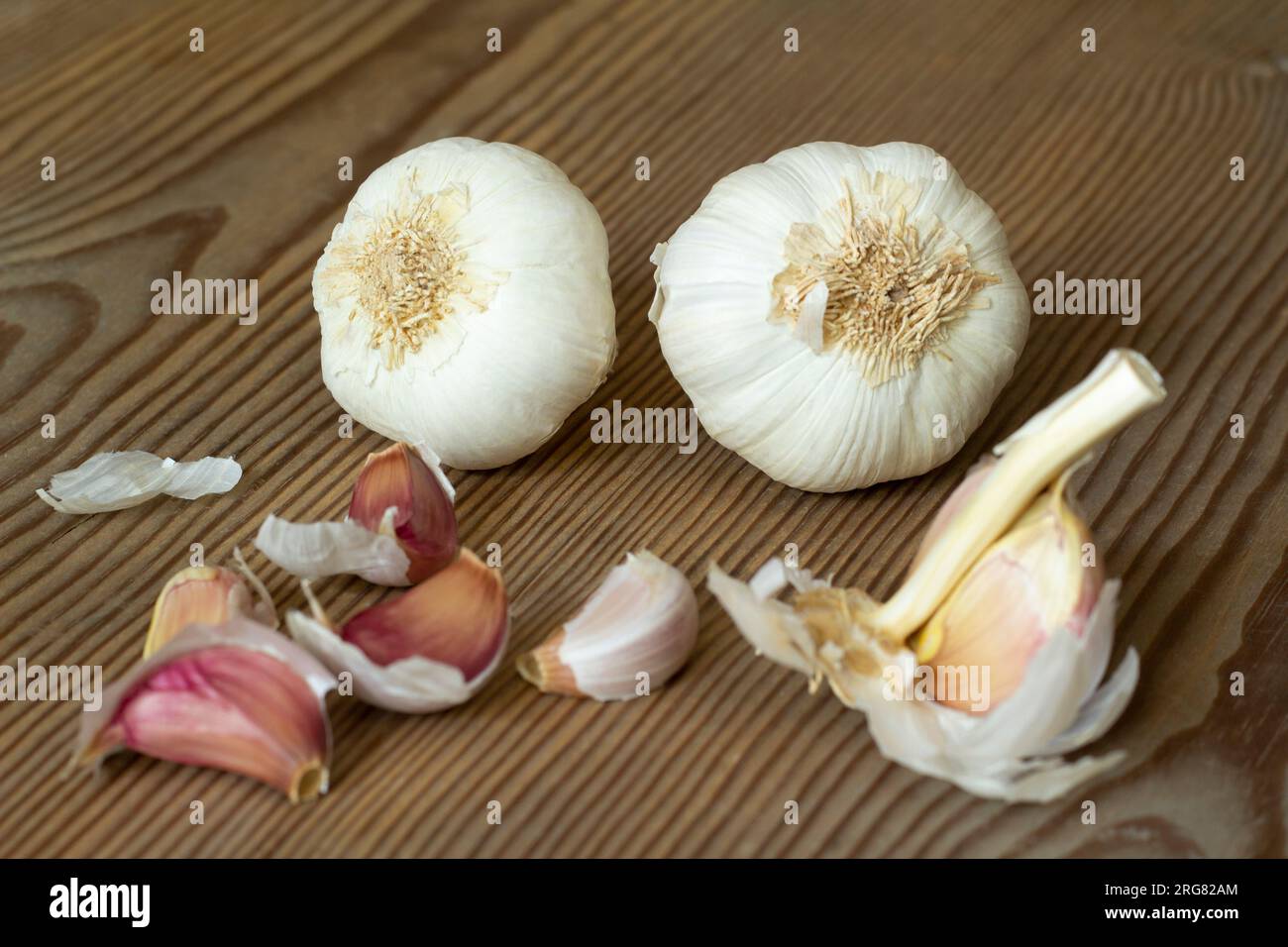Still life of two heads of garlic and a few garlic cloves on the wooden ...