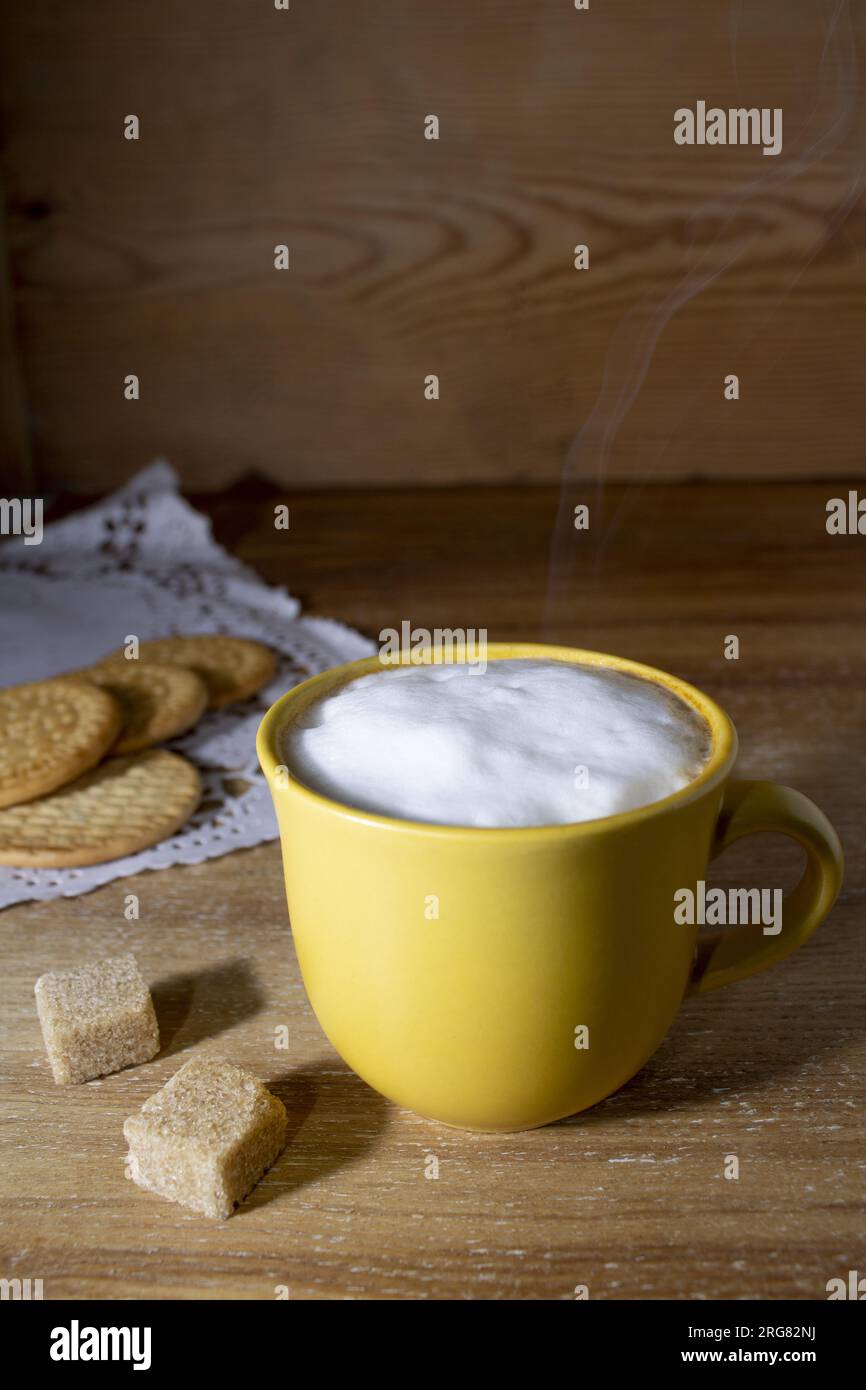 Delicious coffee in a yellow cup with biscuits on the background, all ...