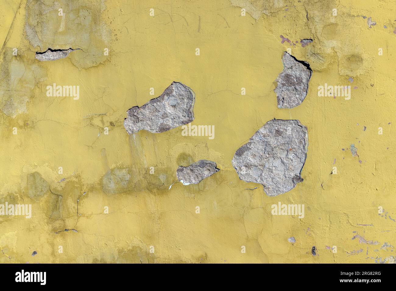 Damaged yellow plaster of a concrete wall, part of a damaged building ...