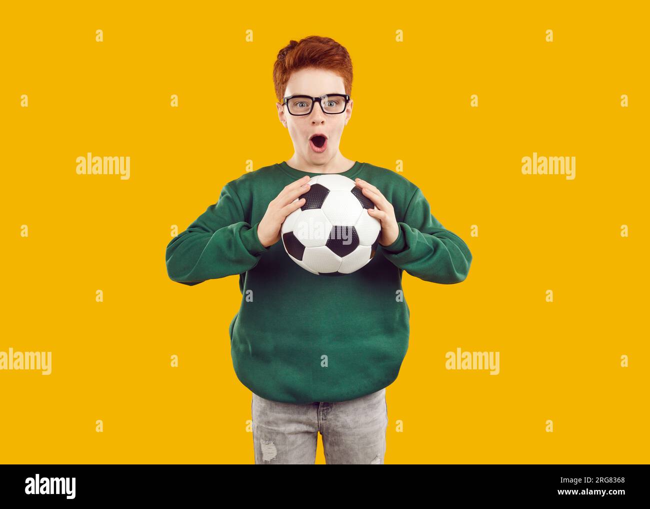 Excited young boy holding football with surprised shocked face and open ...
