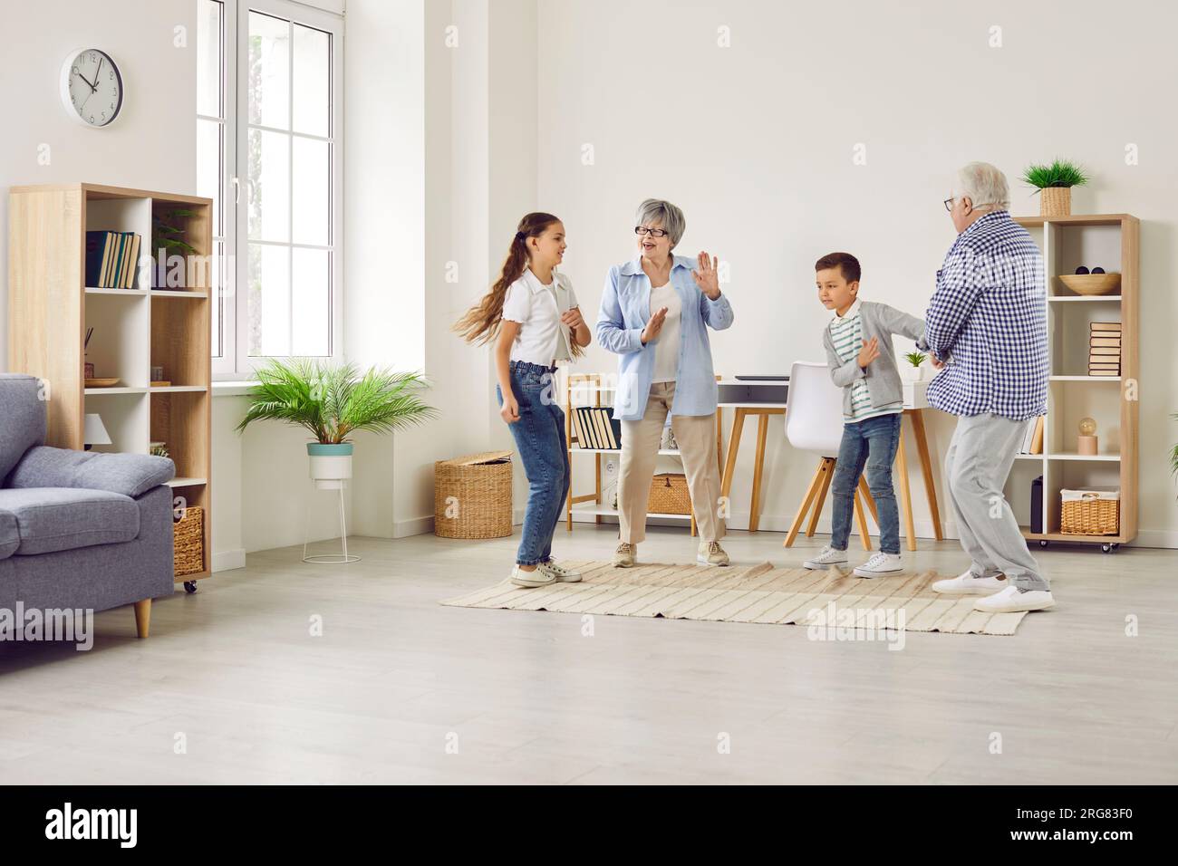 Happy cheerful grandparents having fun with grandchildren dancing at ...