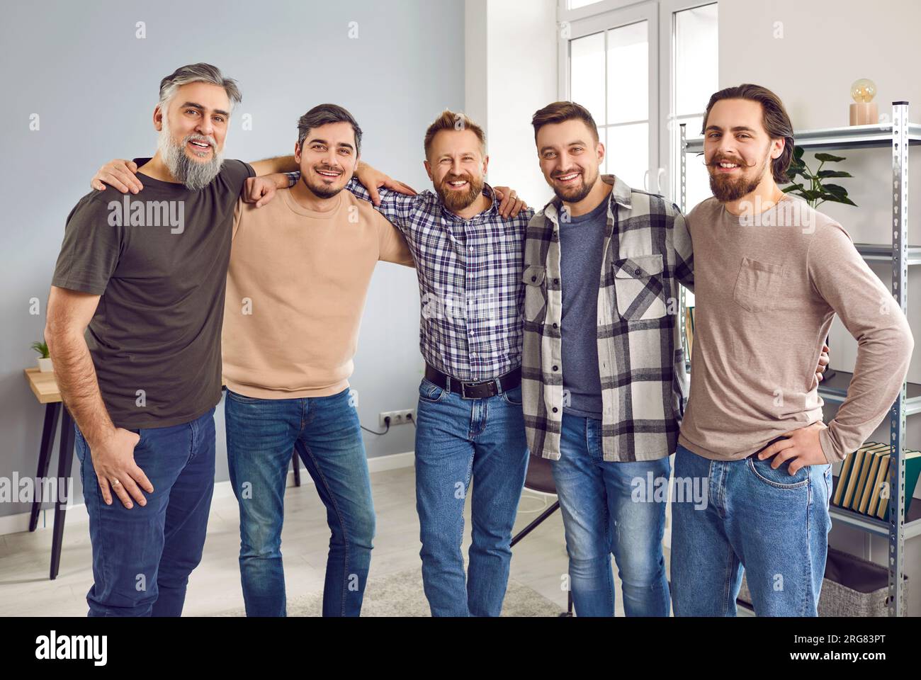 Smiling five male friends standing and hugging shoulders together Stock ...
