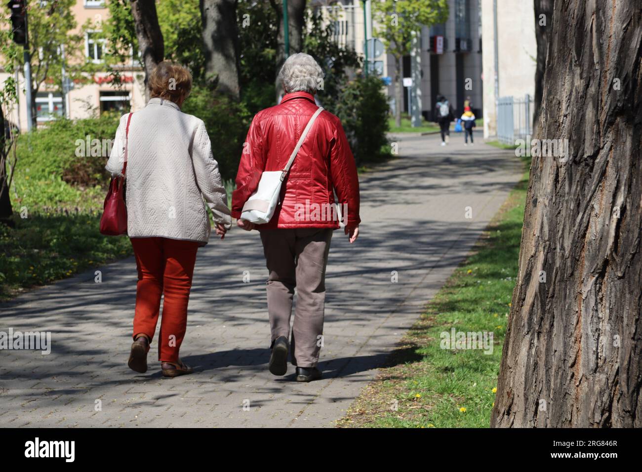 Two retired old women walk through one of the gardens in the sun and in ...