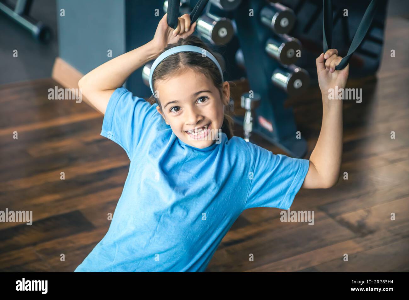 Little girl using trx fitness straps for working with his own weight ...