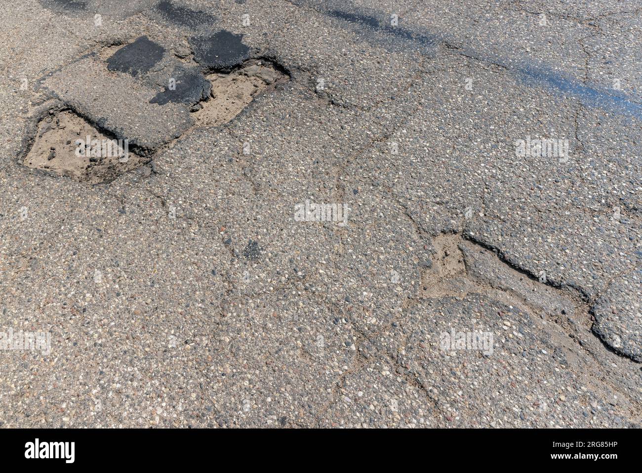 An old paved road with a lot of holes and damage, very poor quality of ...
