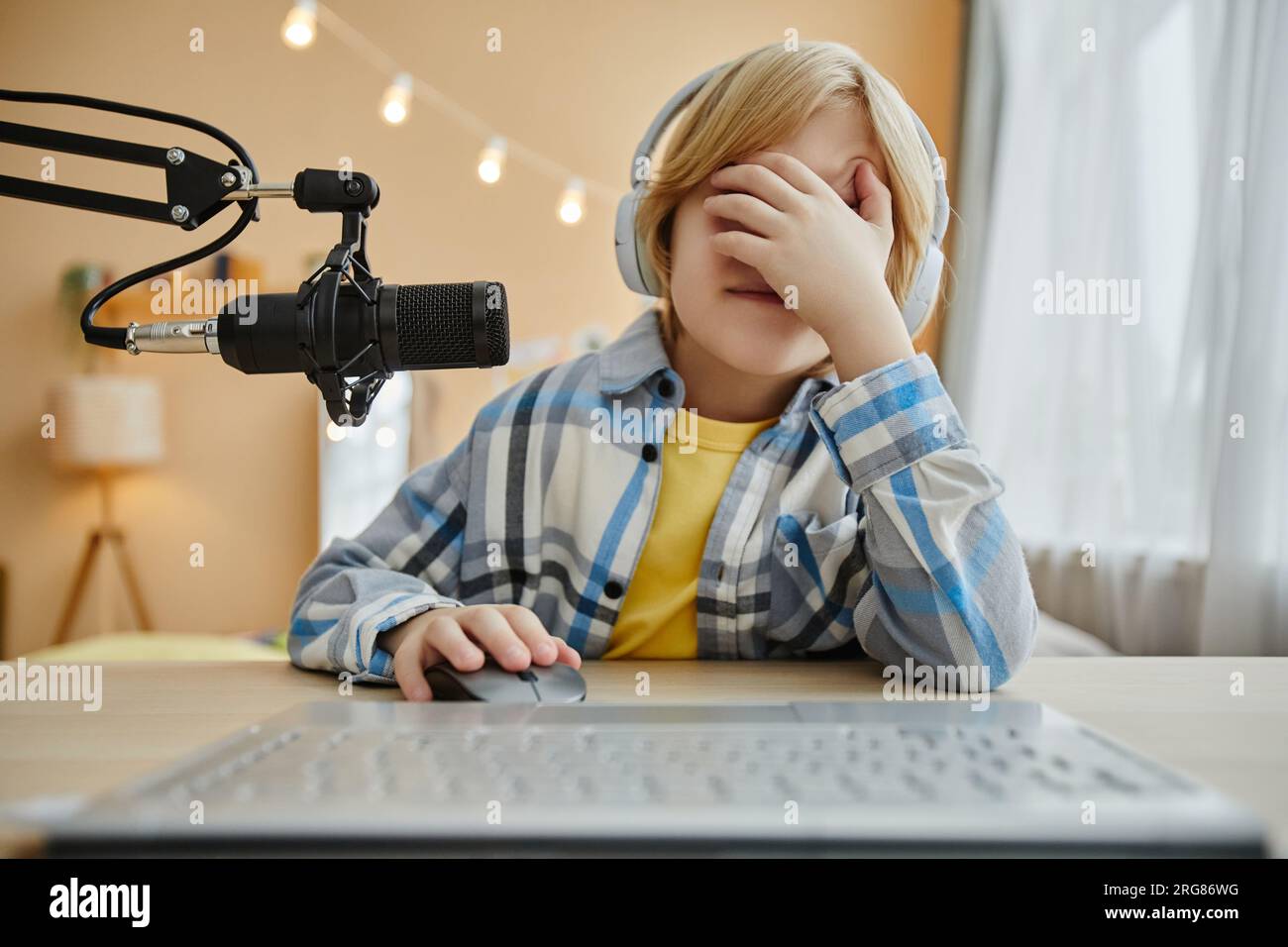 Upset or scared little boy in headphones covering his face with hand ...