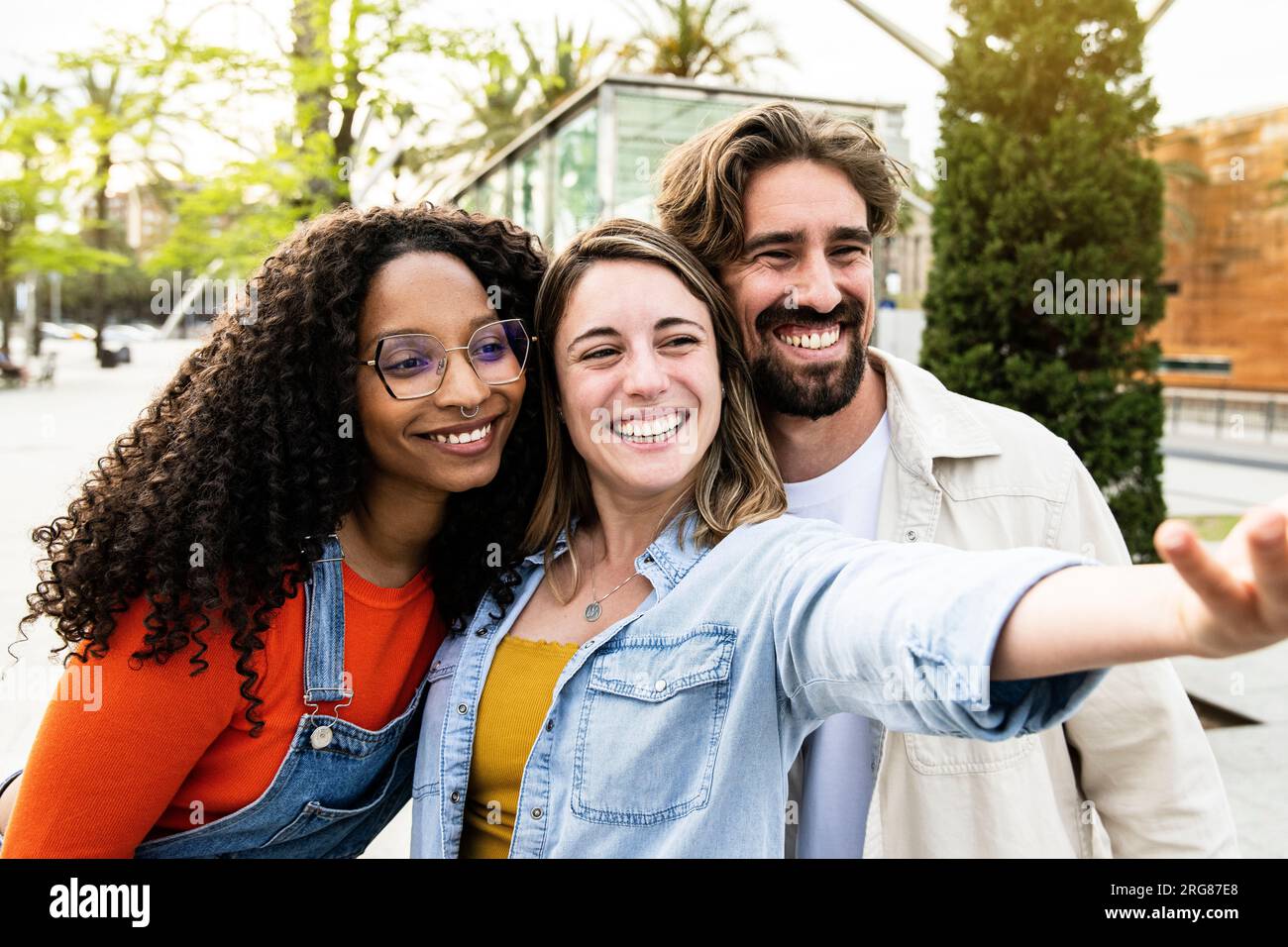 Diverse group of three friends taking a selfie in the street. Cheerful ...