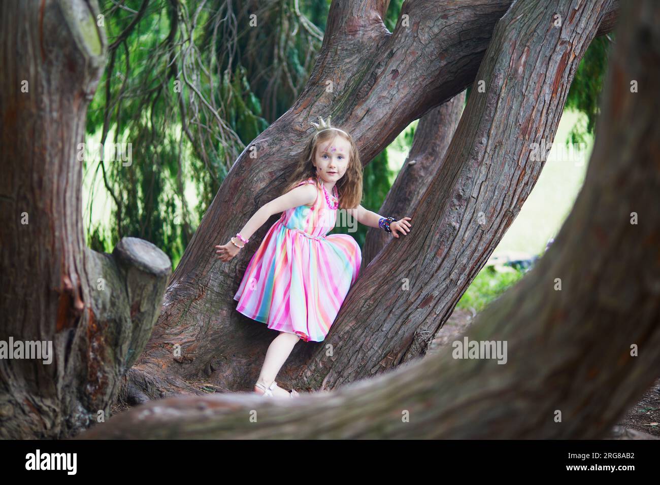 Cute preschooler girl in princess crown playing outdoors in park or ...