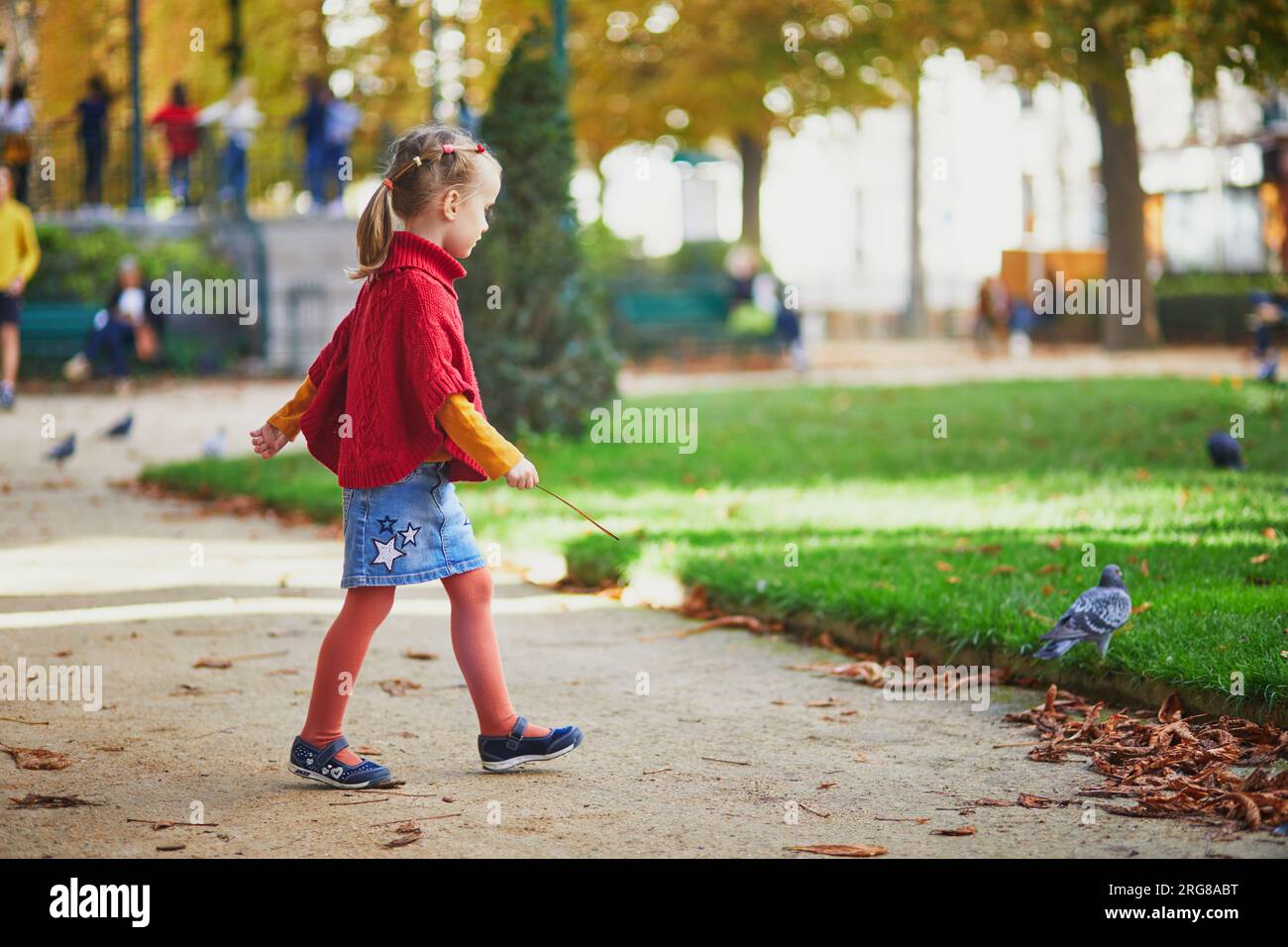 Adorable preschooler girl enjoying nice and sunny autumn day outdoors ...