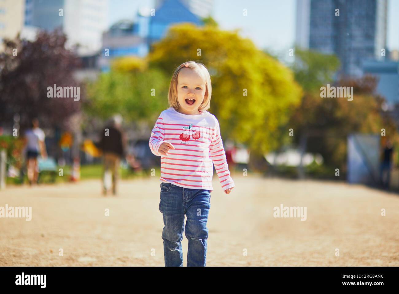 Cheerful toddler girl running on a street of Paris, France. Happy child ...