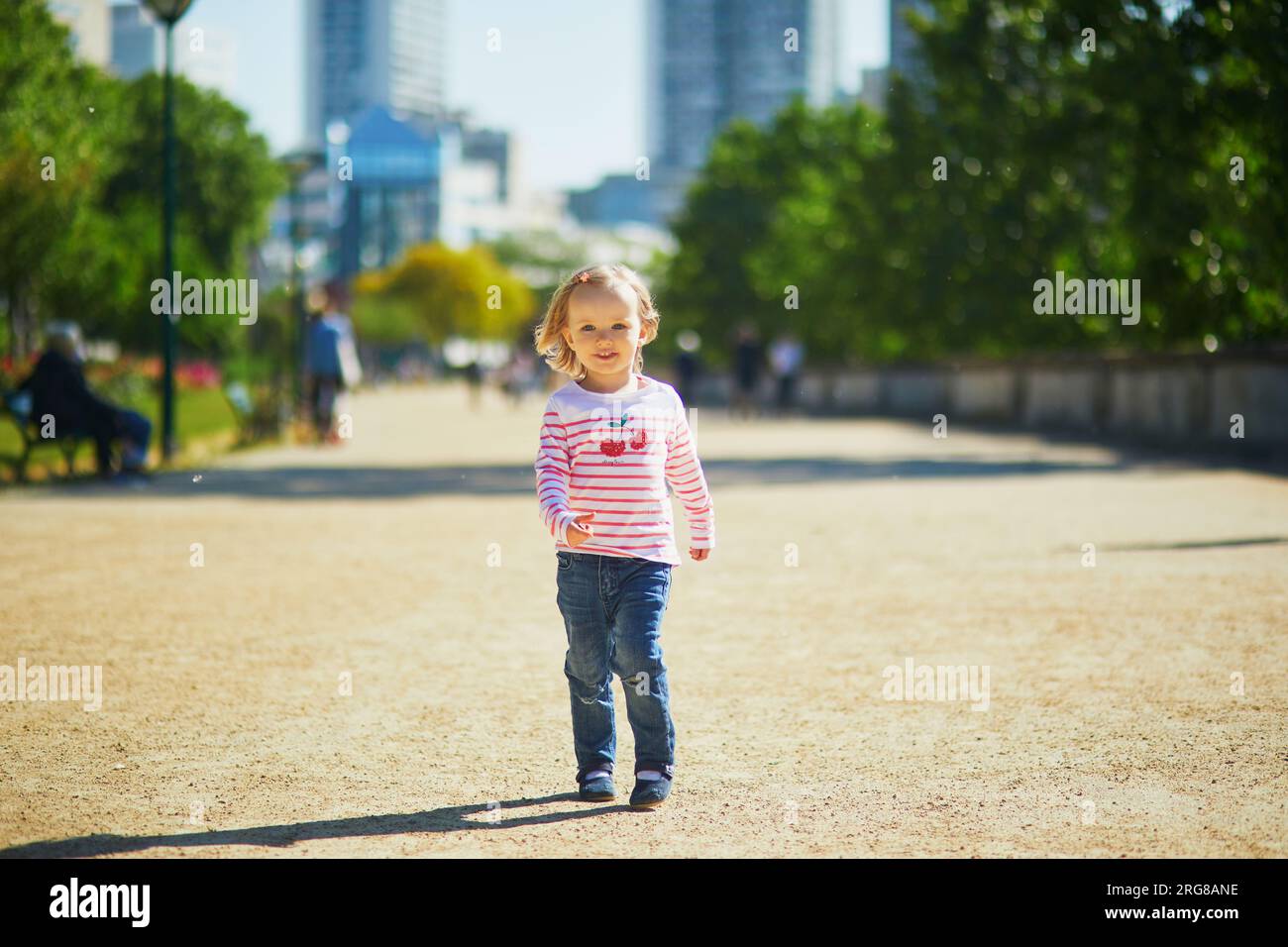 Cheerful toddler girl running on a street of Paris, France. Happy child ...