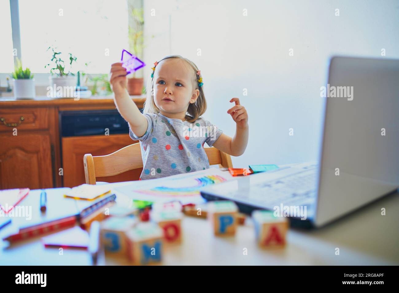 Toddler girl learning shapes in front of laptop. Kid using computer to ...