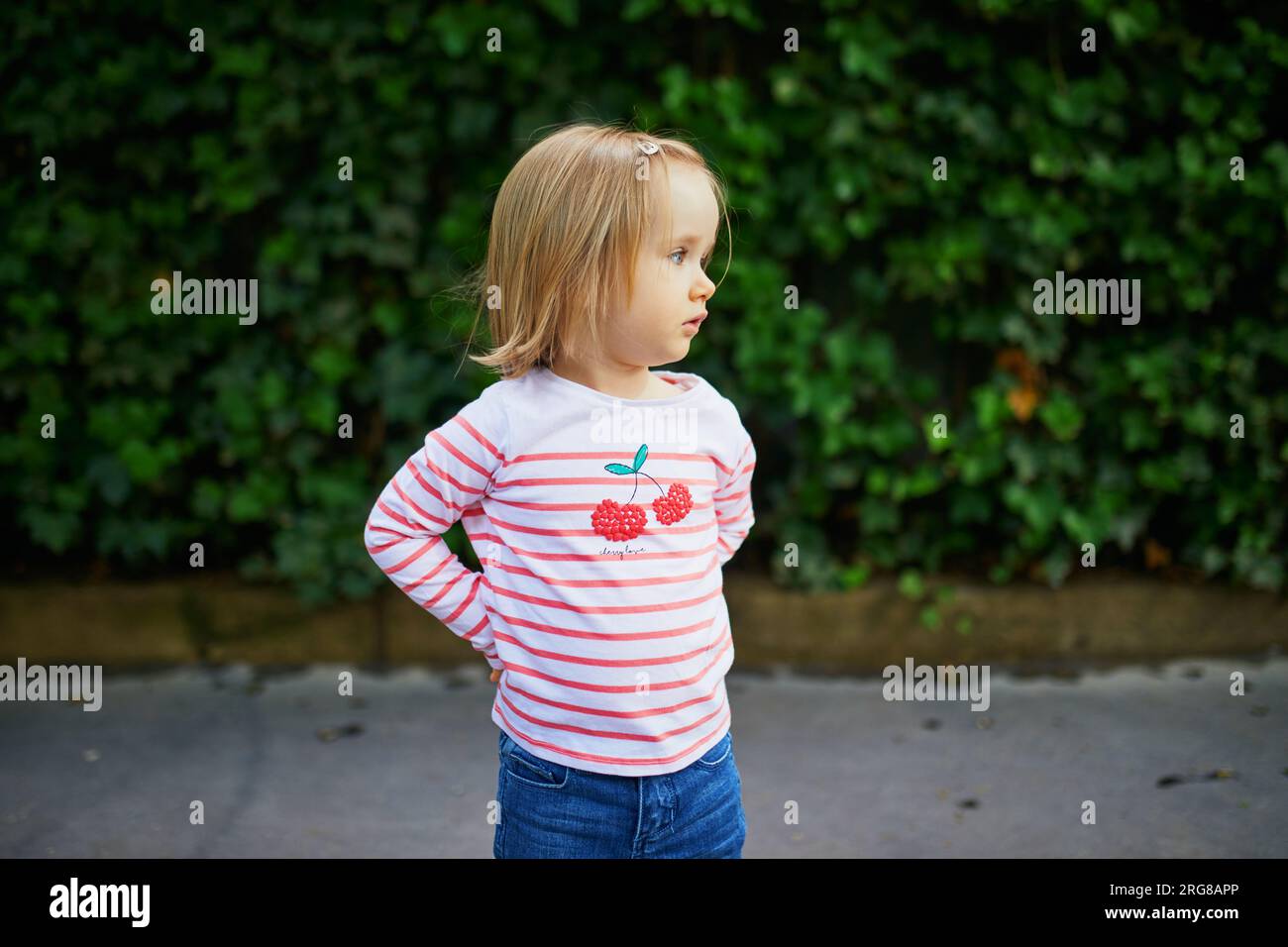 Adorable toddler girl walking on a city street. Happy child playing ...
