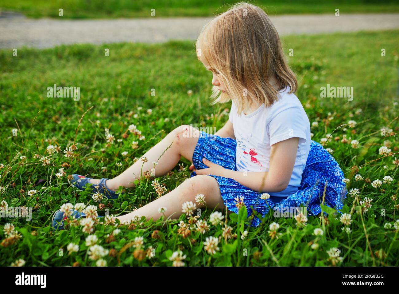 Cute little girl sitting on the ground after falling down. Child ...