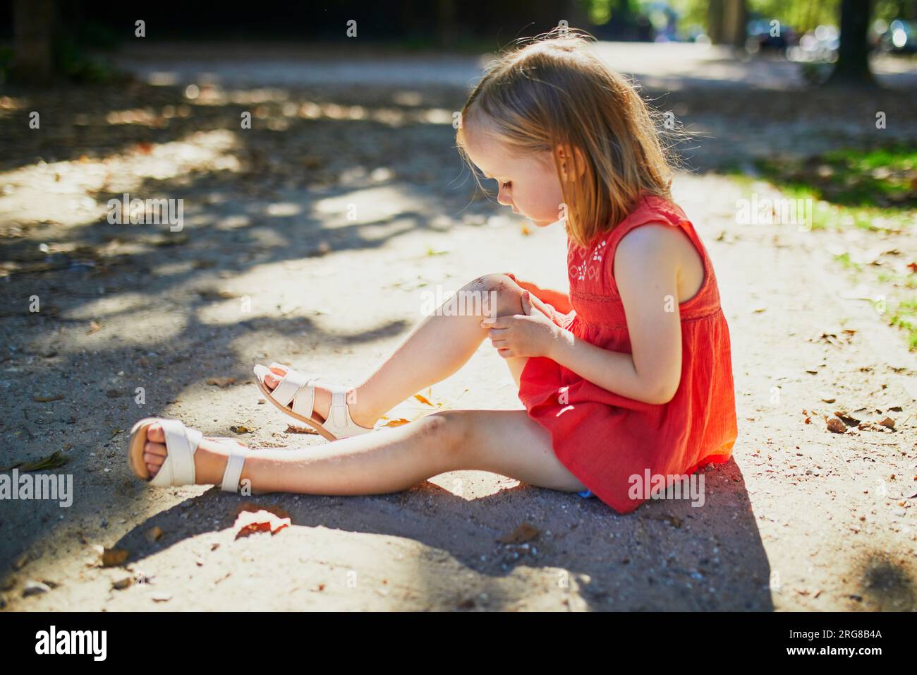 Cute little girl sitting on the ground after falling down. Child ...
