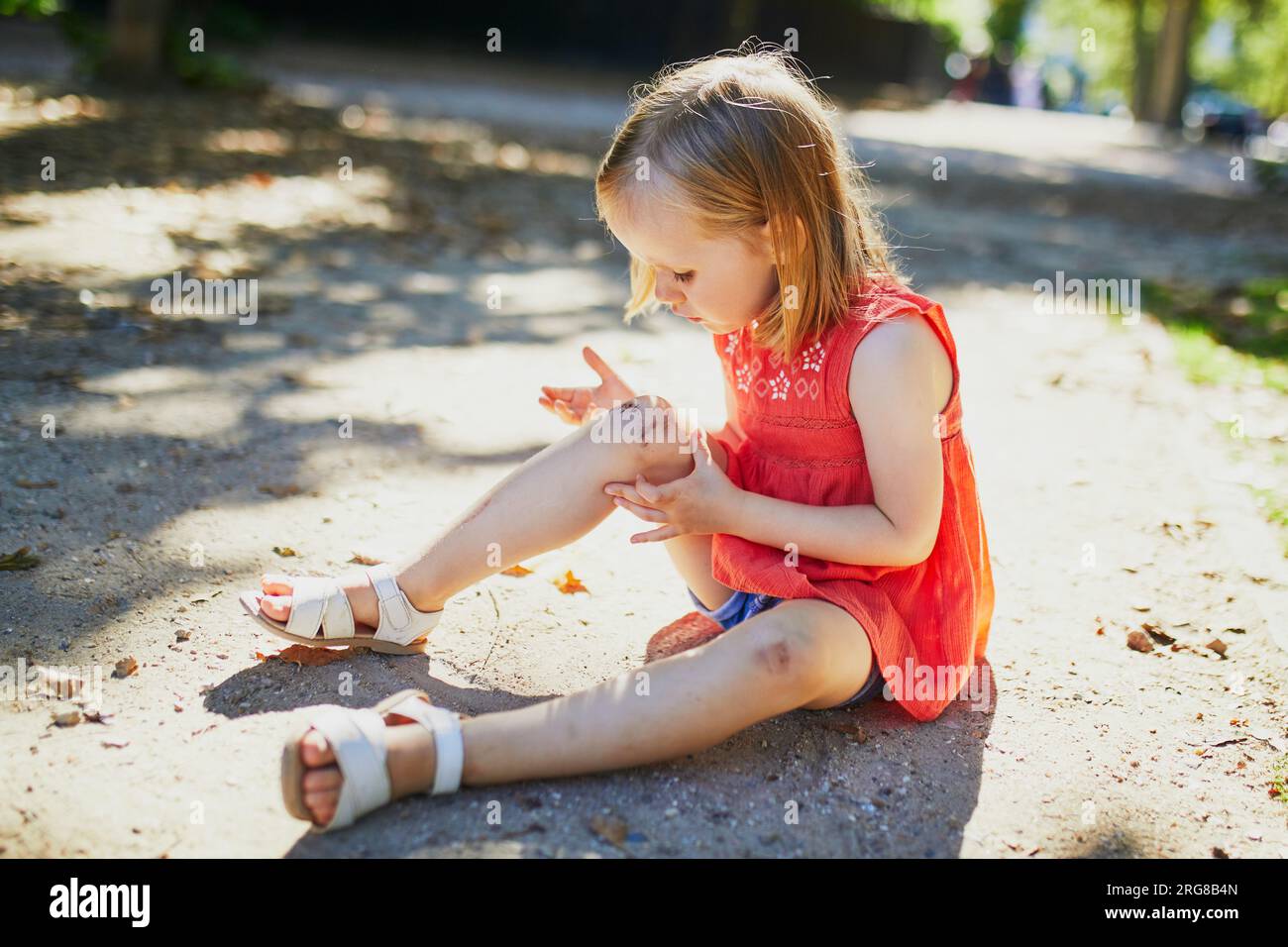 Cute little girl sitting on the ground after falling down. Child ...