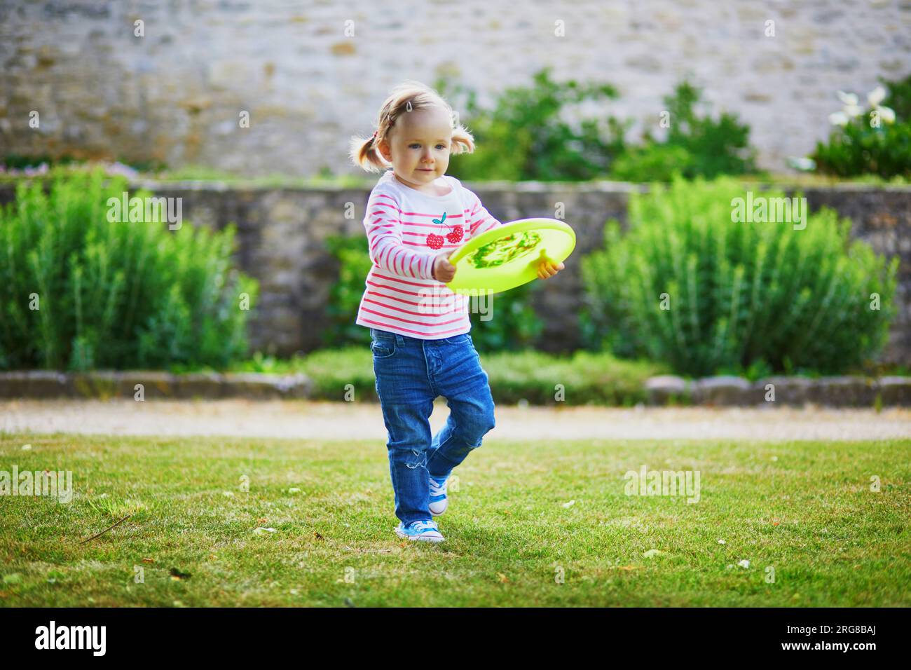 Adorable toddler girl playing flying disc. Child having fun outdoors on ...