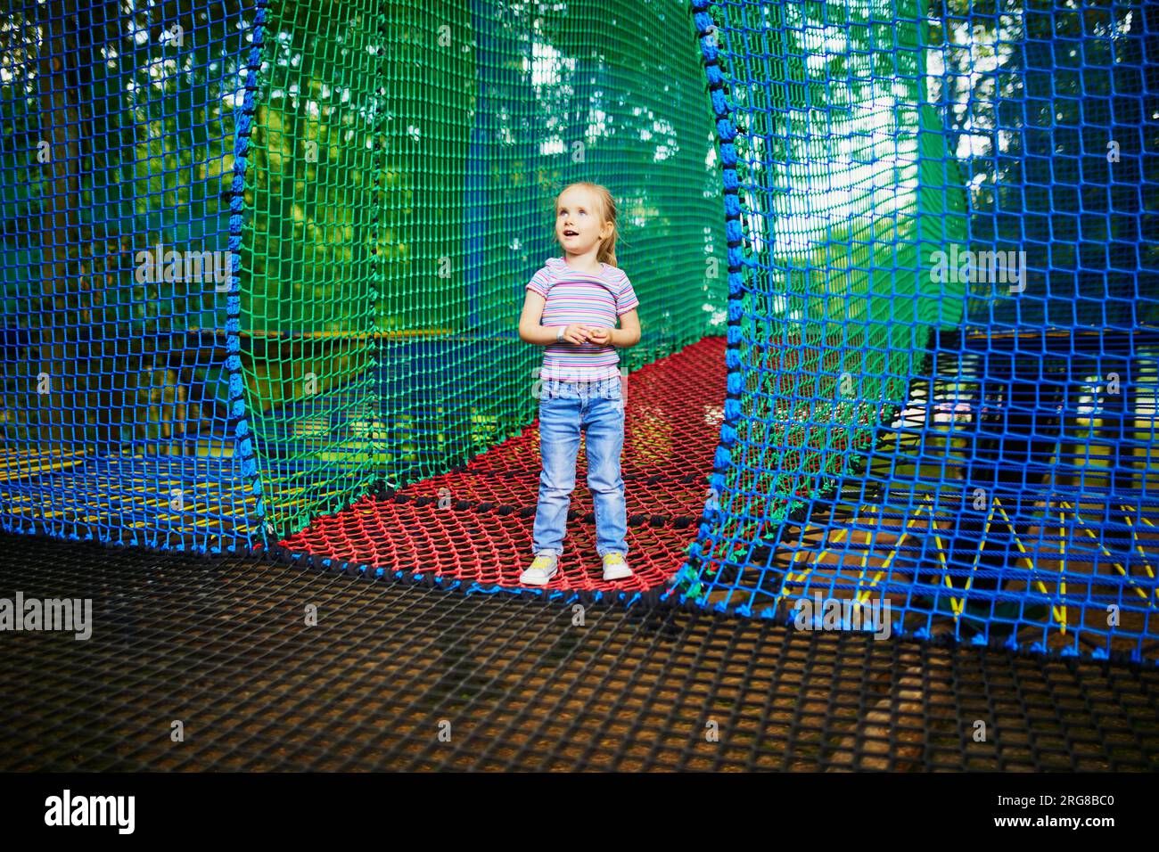 Adorable little girl having fun in adventure park. Child on tree top ...