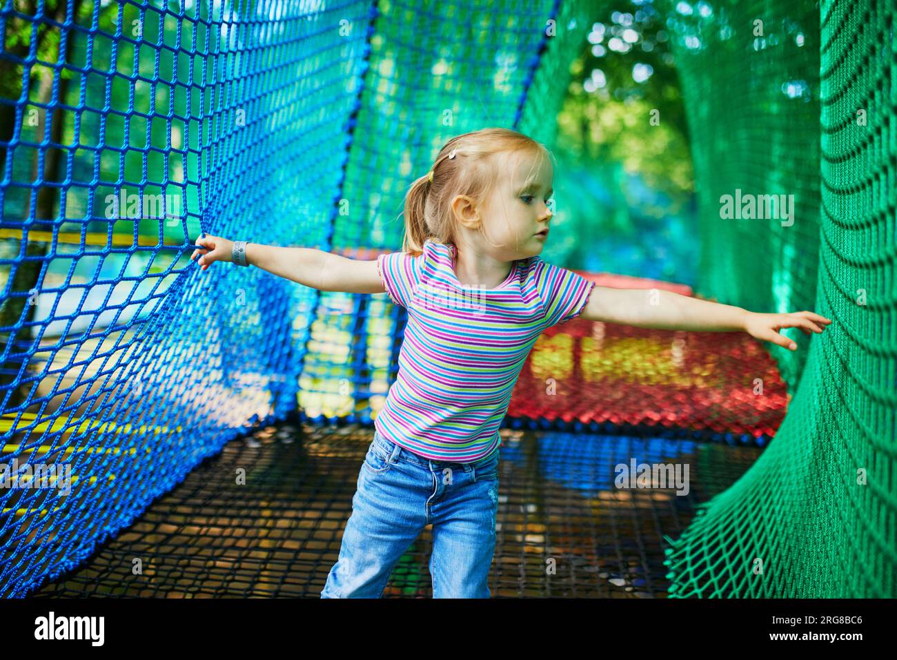 Adorable little girl having fun in adventure park. Child on tree top ...