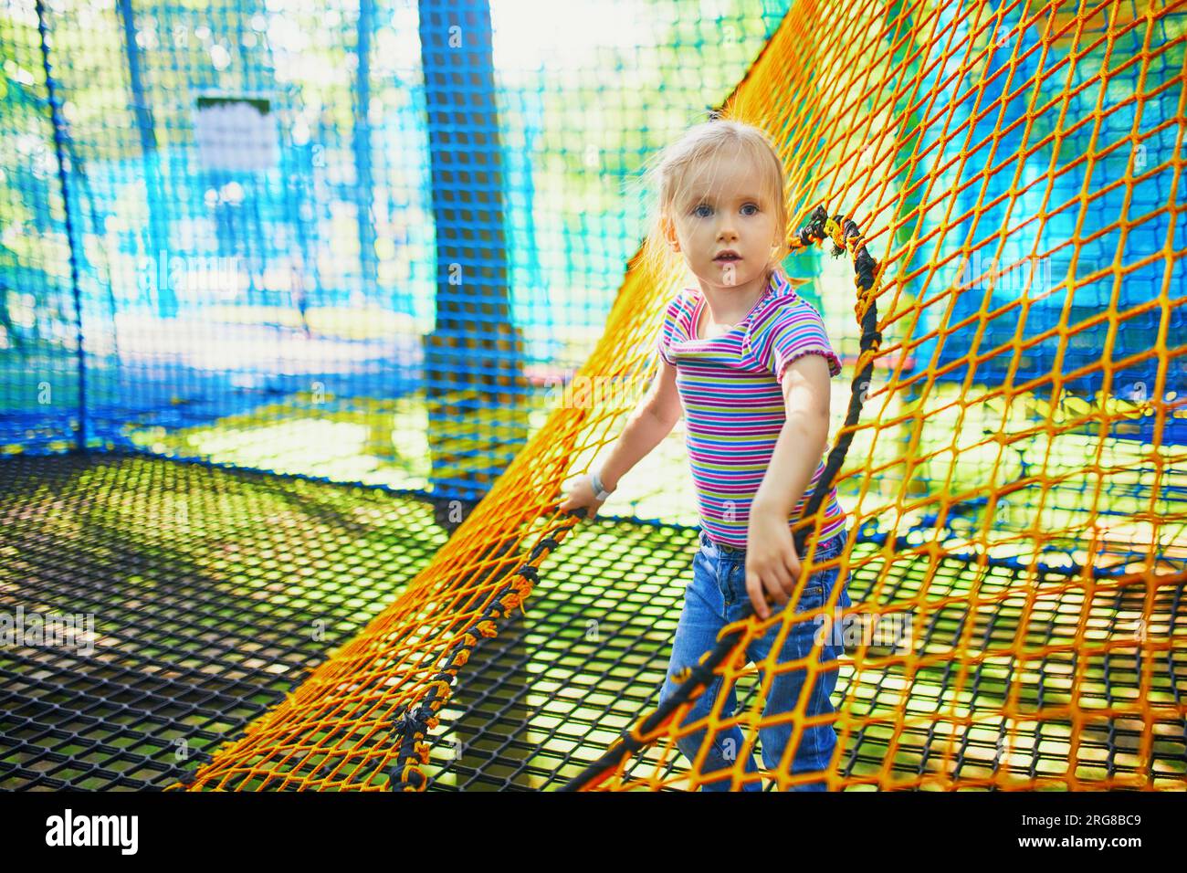 Adorable little girl having fun in adventure park. Child on tree top ...