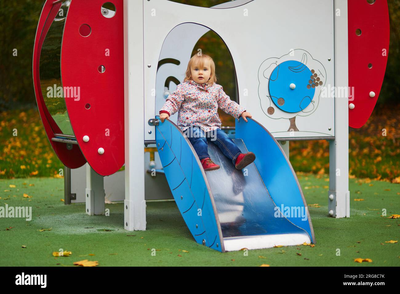 Adorable little girl on playground on a fall day. Toddler trying to ...