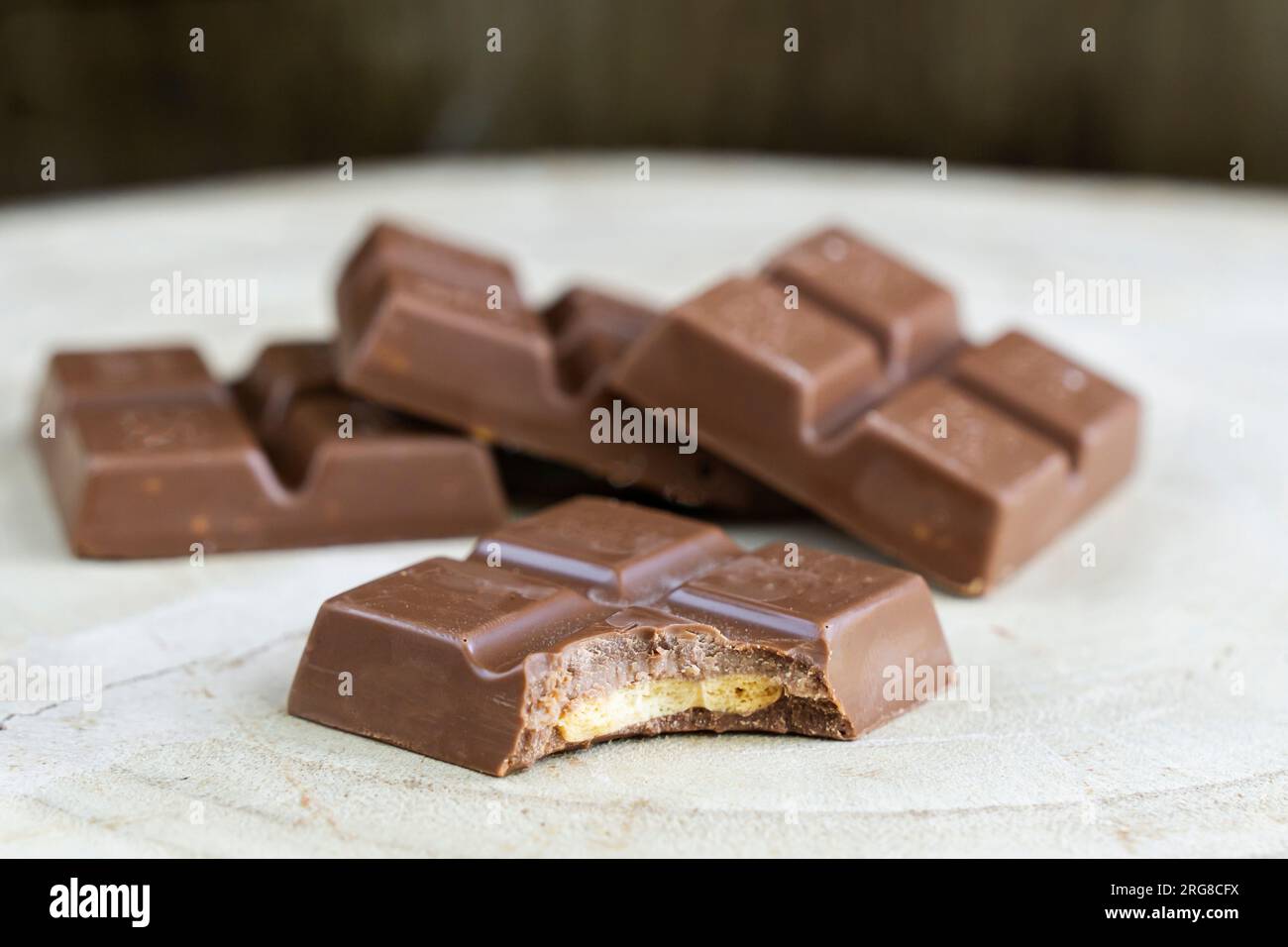 Dark chocolate squares filled with cookies on a natural wood table ...