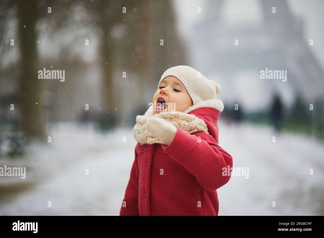 Adorable toddler girl catching snowflakes with her tongue near the ...