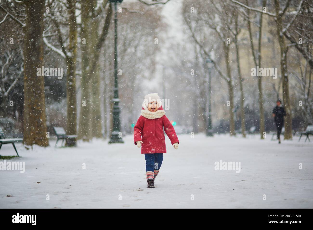 Adorable toddler girl on a day with heavy snowfall. Happy child playing ...