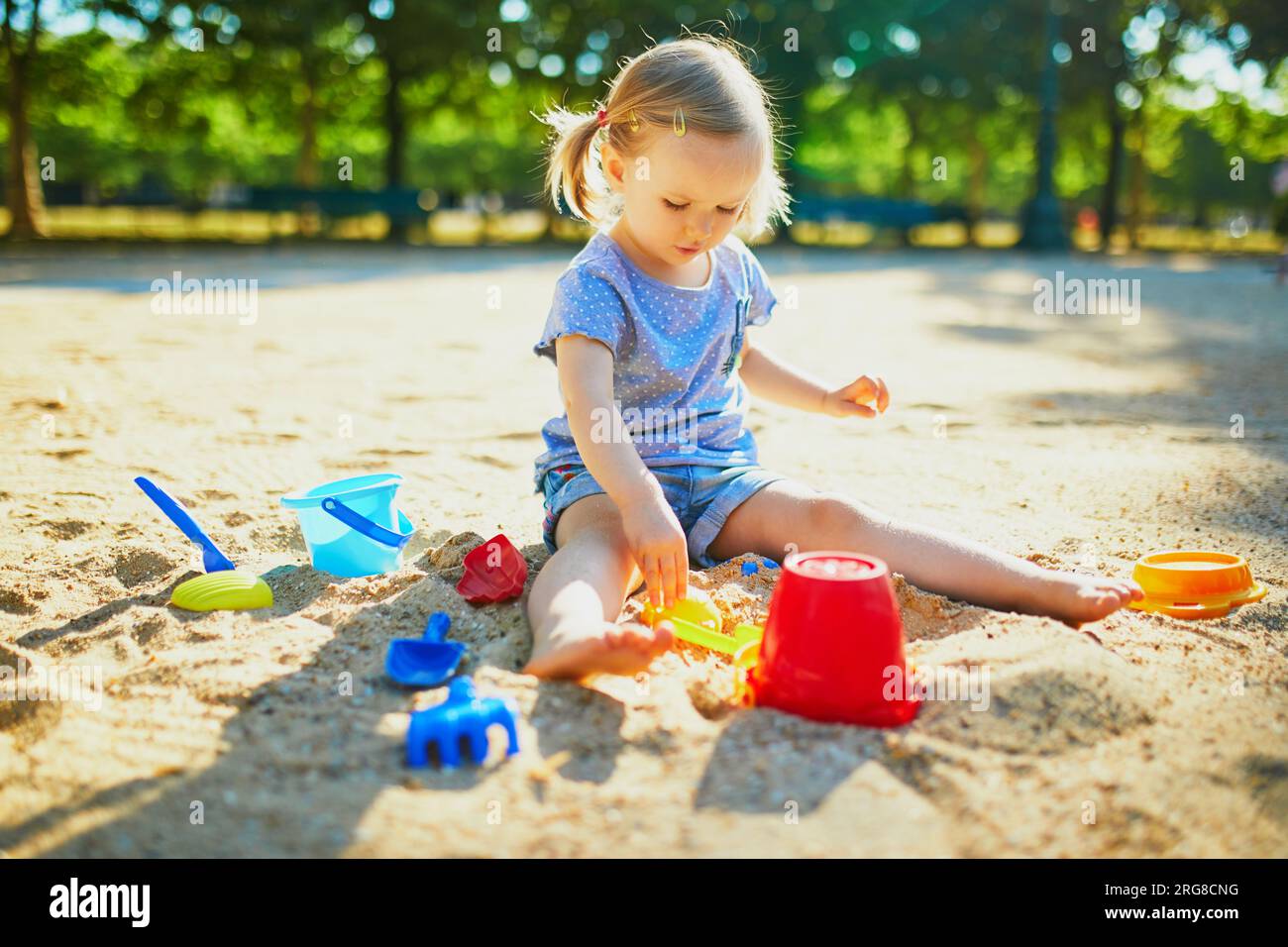 Adorable little girl having fun on playground in sandpit. Toddler ...