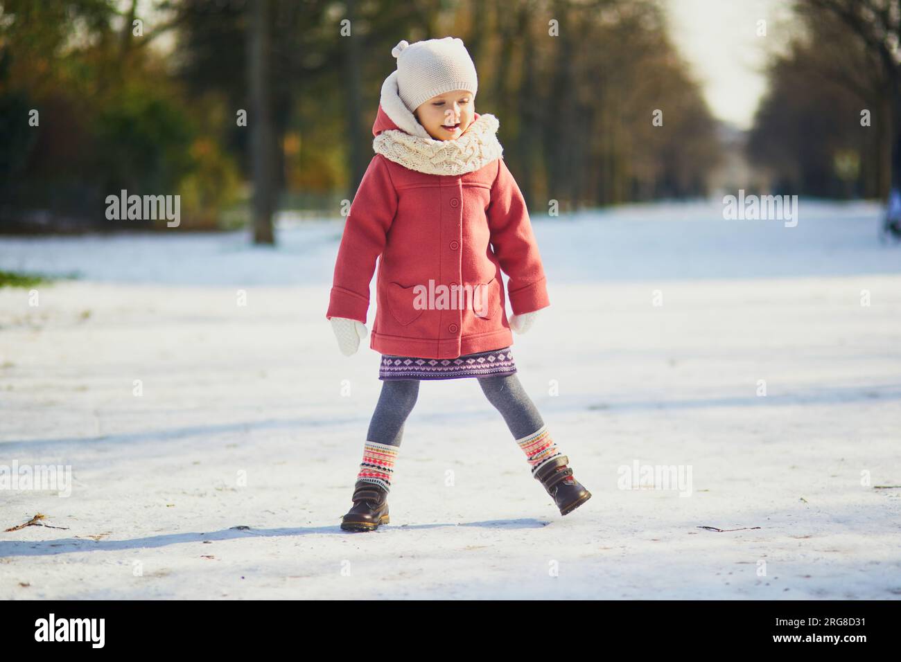 Adorable toddler girl on a sunny snow day. Happy child playing with ...