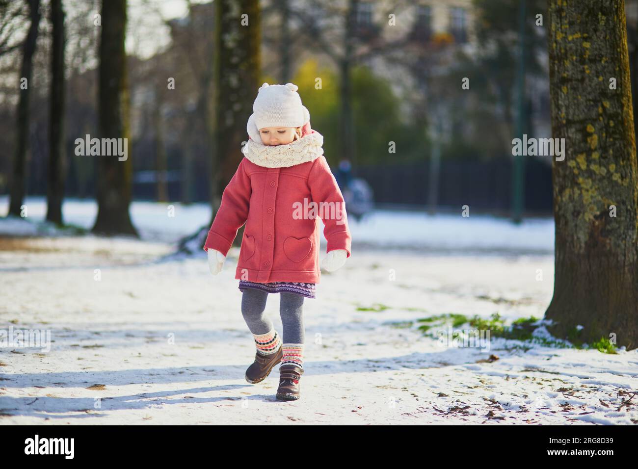 Adorable toddler girl on a sunny snow day. Happy child playing with ...