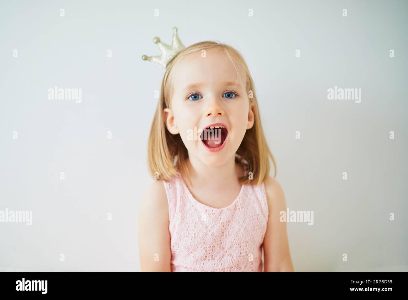 Adorable little girl in pink dress and golden crown dressed as princess ...