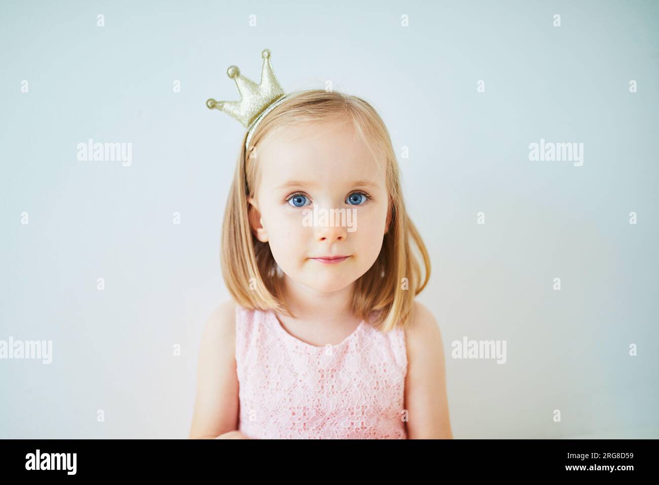 Adorable little girl in pink dress and golden crown dressed as princess ...