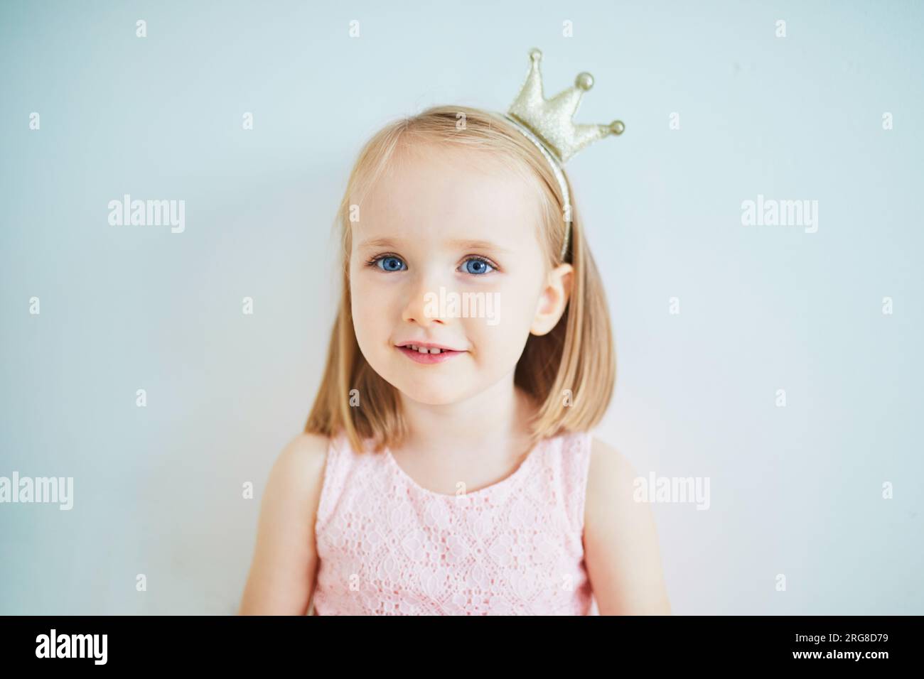 Adorable little girl in pink dress and golden crown dressed as princess ...