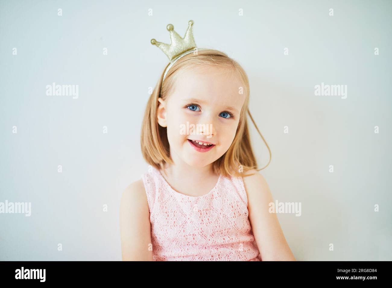 Adorable little girl in pink dress and golden crown dressed as princess ...