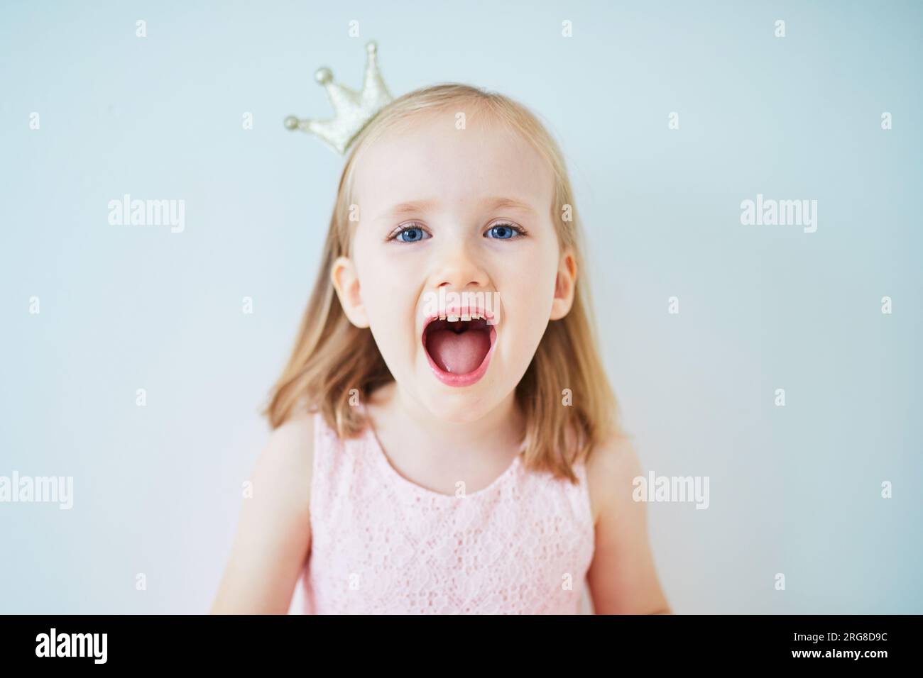 Adorable little girl in pink dress and golden crown dressed as princess ...